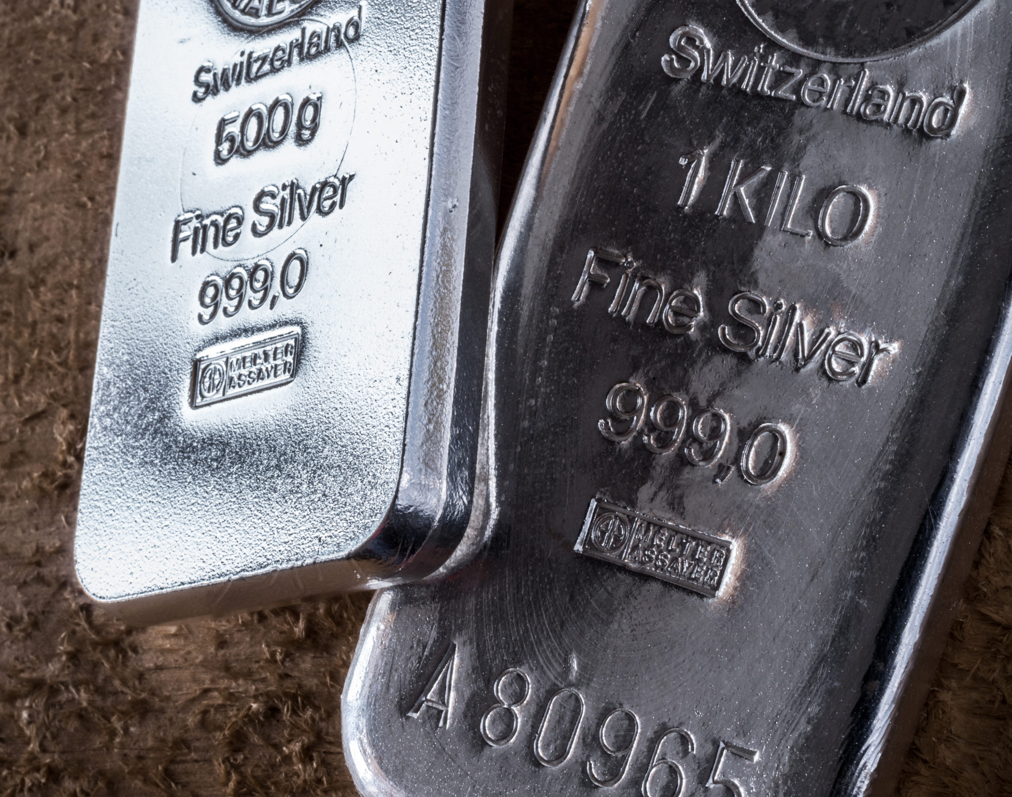 Silver bullion bars. Two fine silver bars on a.background of a rough ...