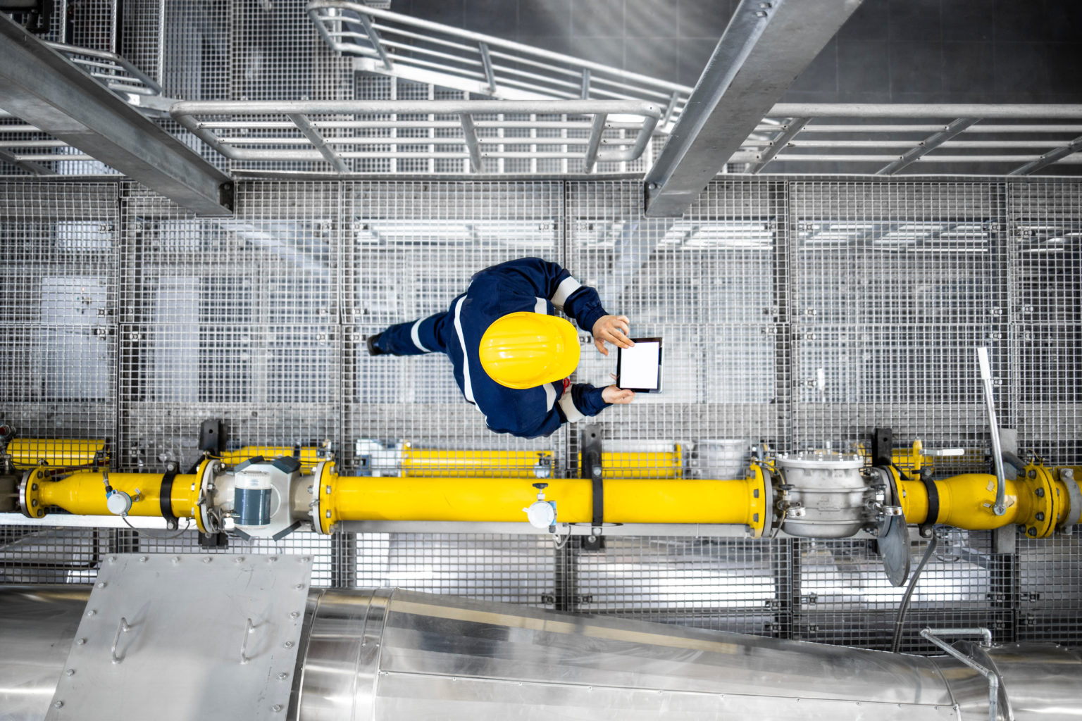 Top view of refinery worker walking by gas pipes, checking gasol ...