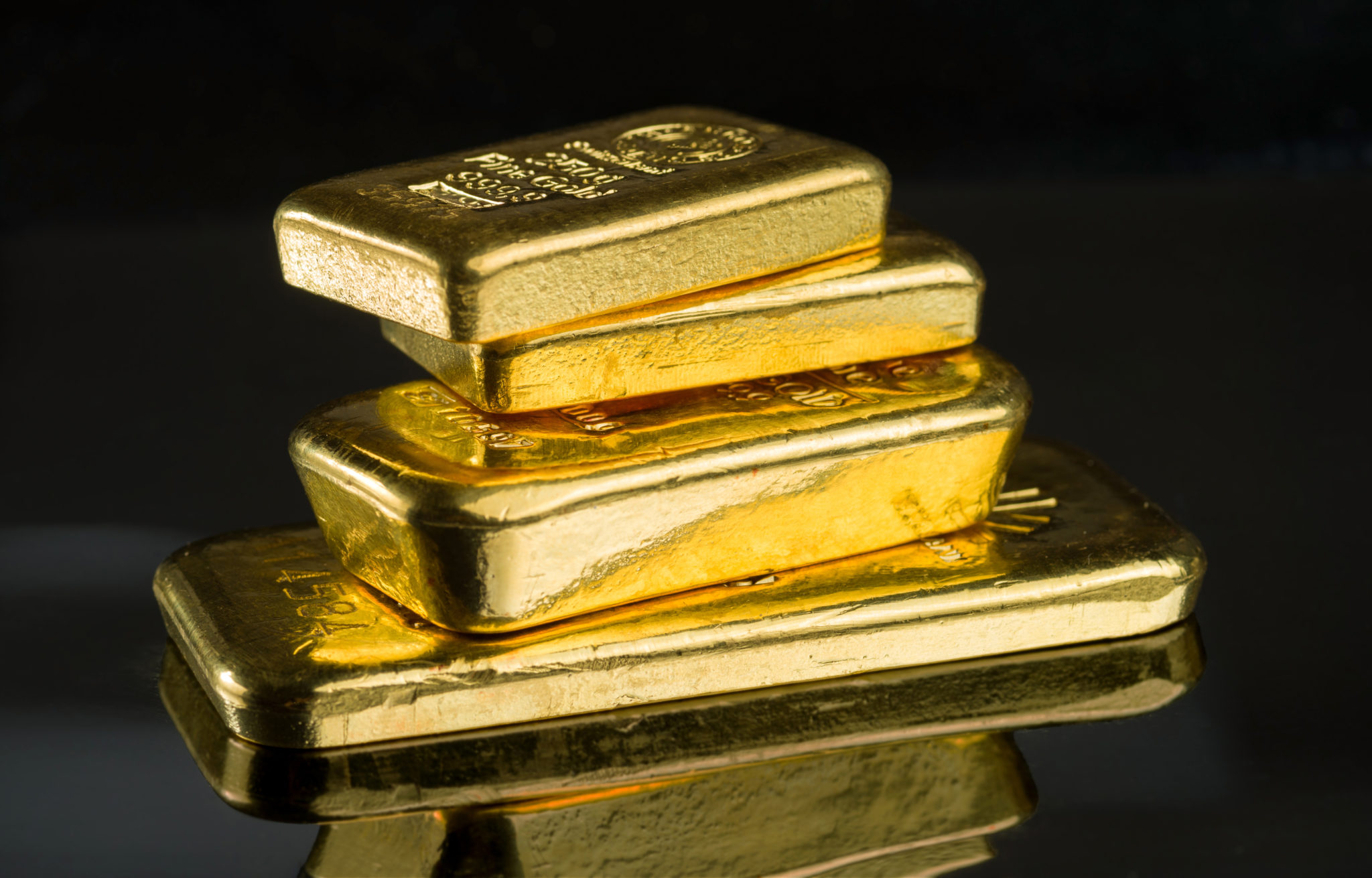 Several gold bars of different weight on a dark mirror surface ...