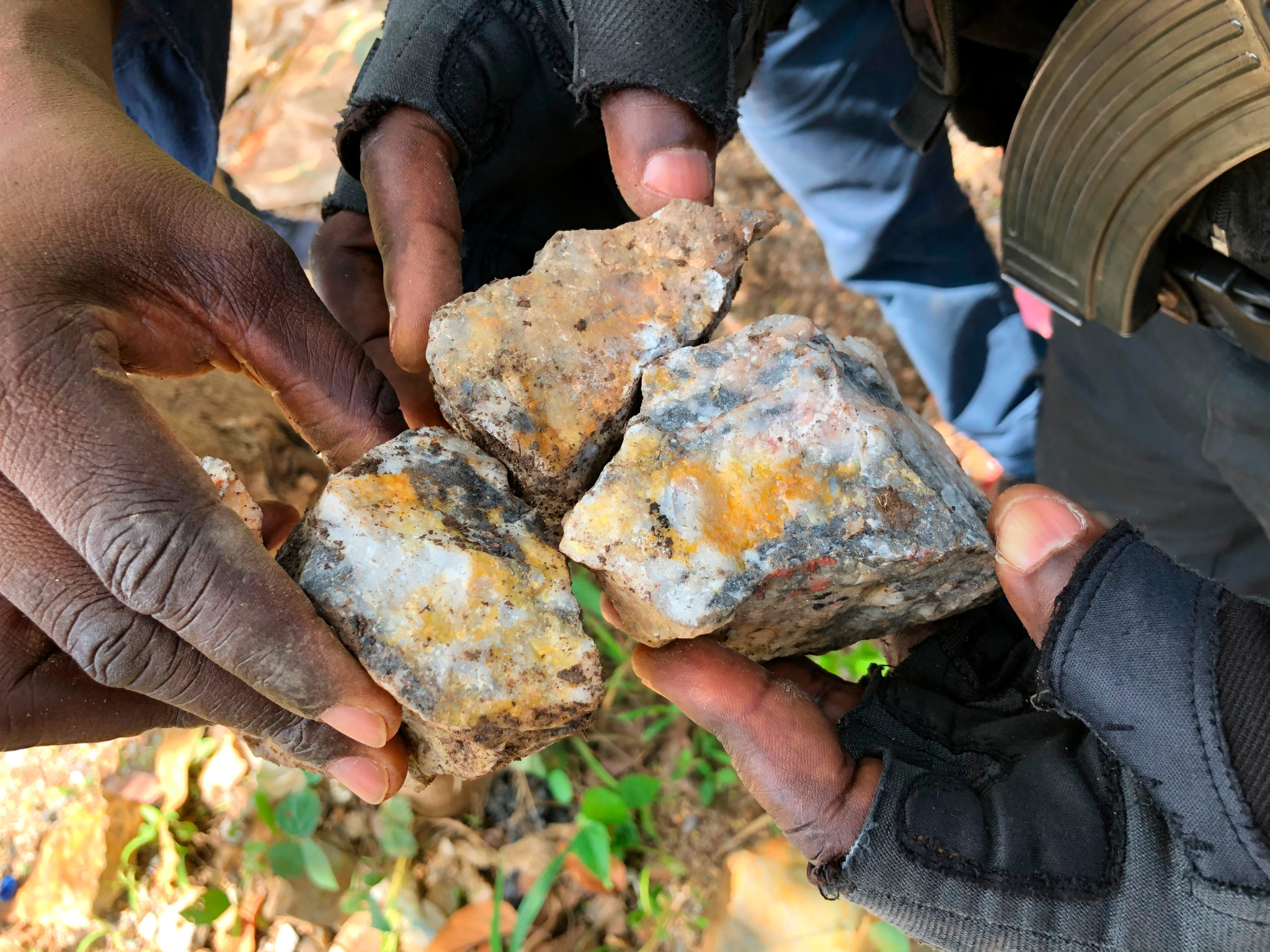 Ghanaian policemen observe some ore seized on pits operated by ...